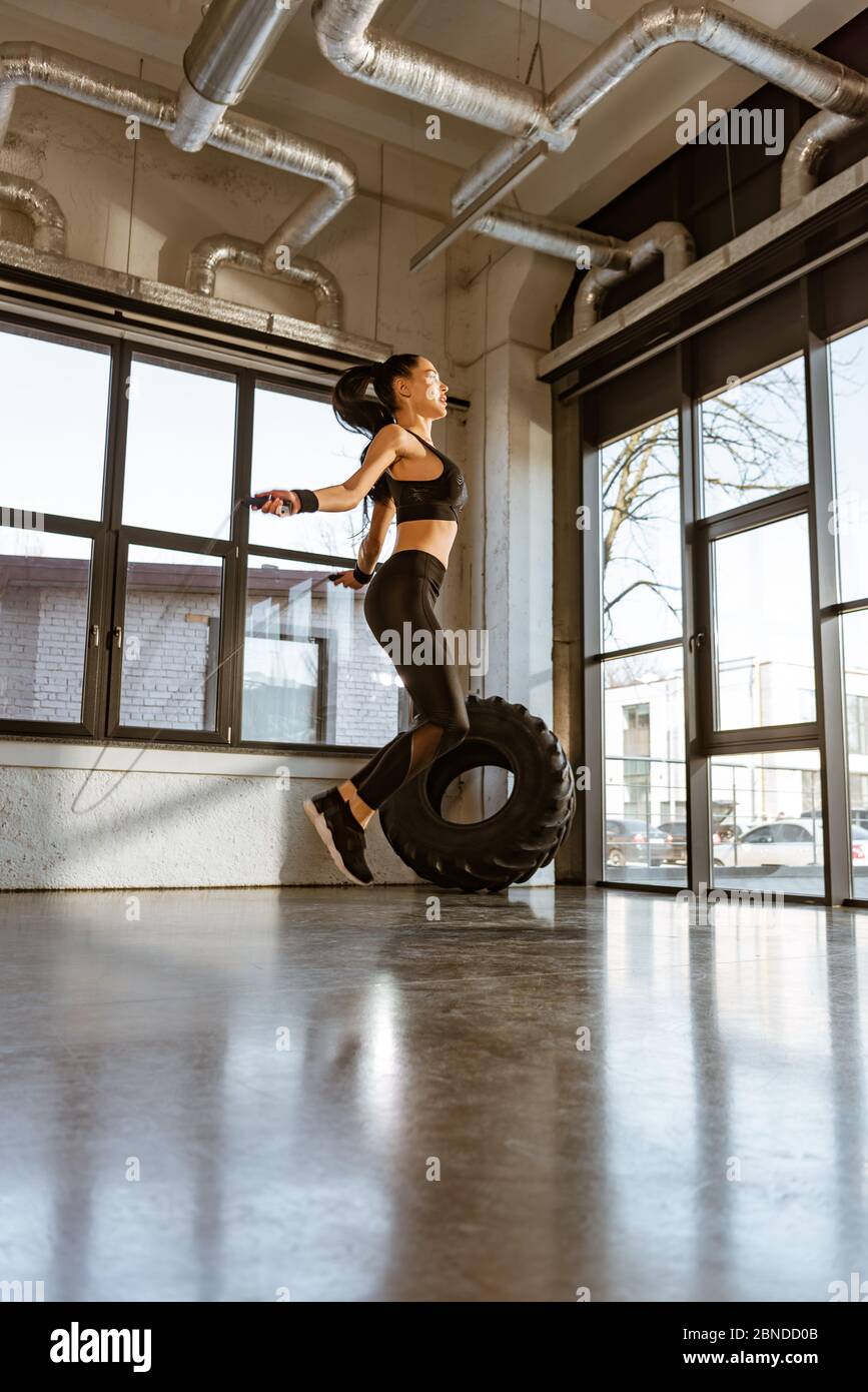Side view of sportswoman jumping with skipping rope in gym Stock Photo ...