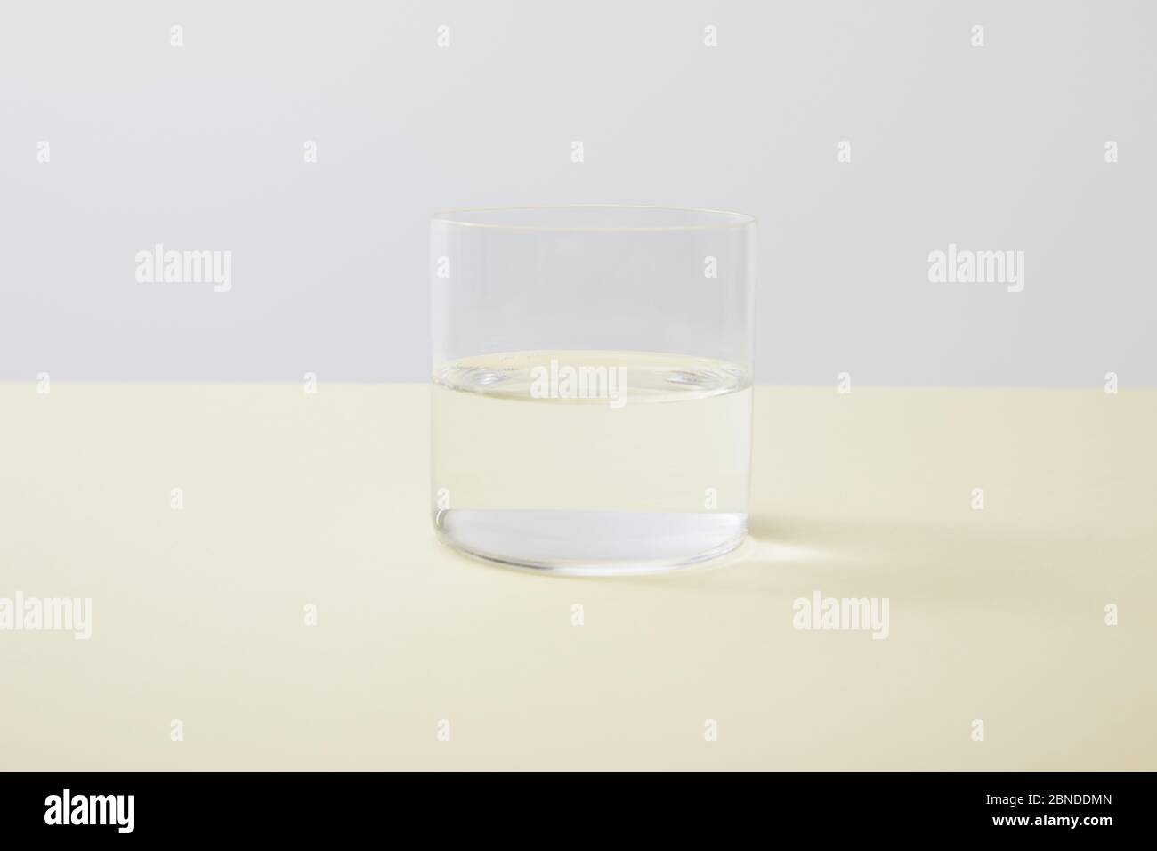 Glass with water on yellow surface isolated on grey Stock Photo - Alamy