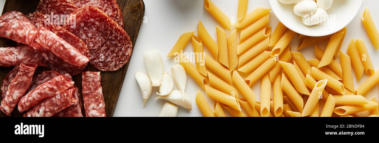 Panoramic shot of meat platter, garlic, pasta and bowl with mozzarella ...