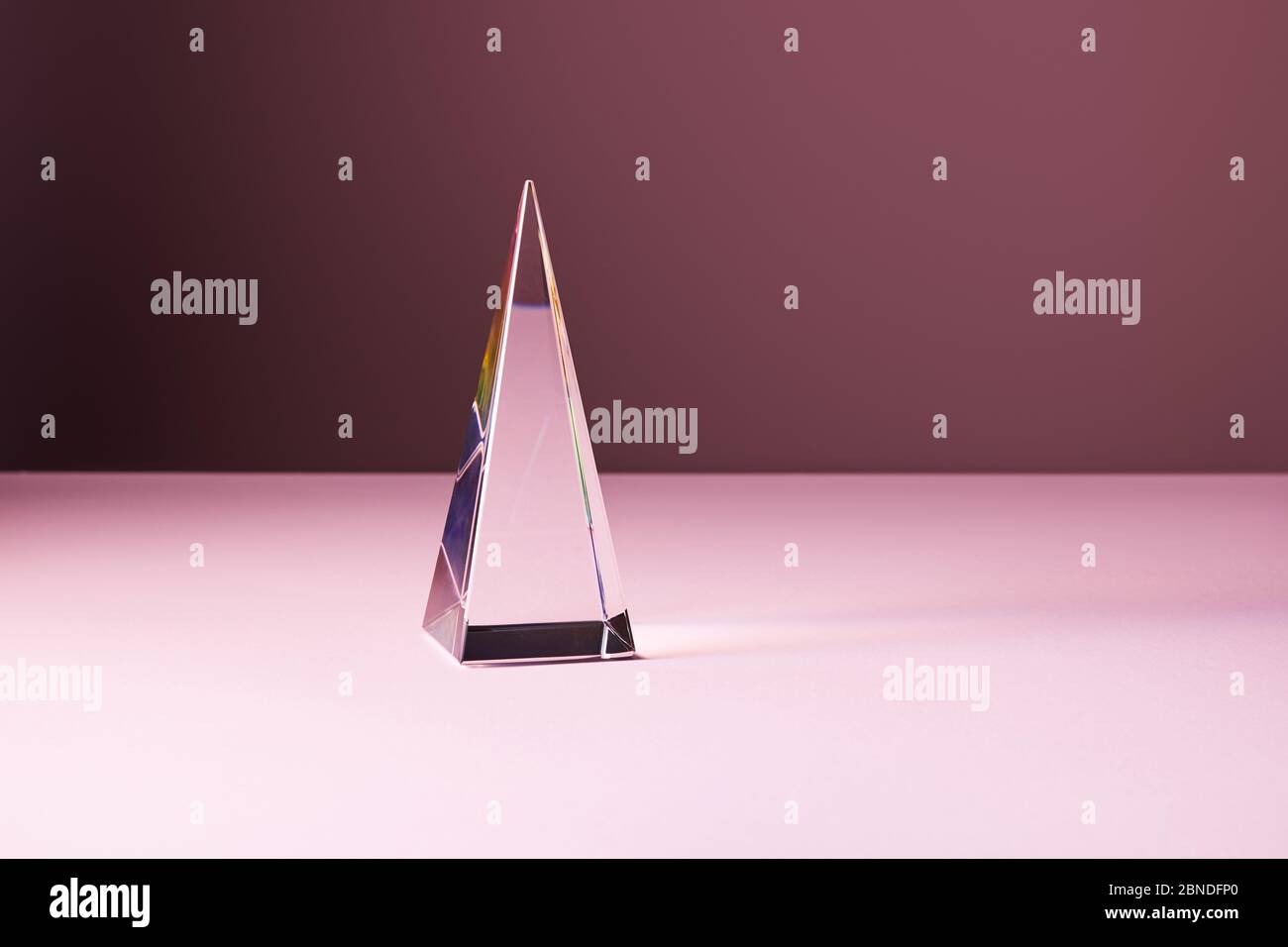 crystal transparent pyramid with light reflection on pink background ...