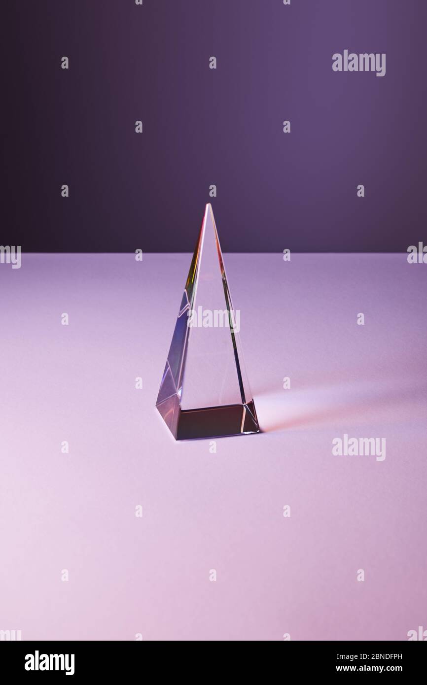 crystal transparent pyramid with light reflection on violet and purple ...