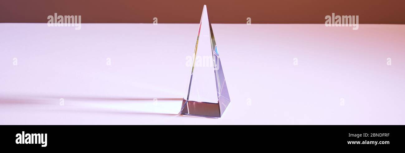 crystal transparent pyramid with light reflection on brown background ...