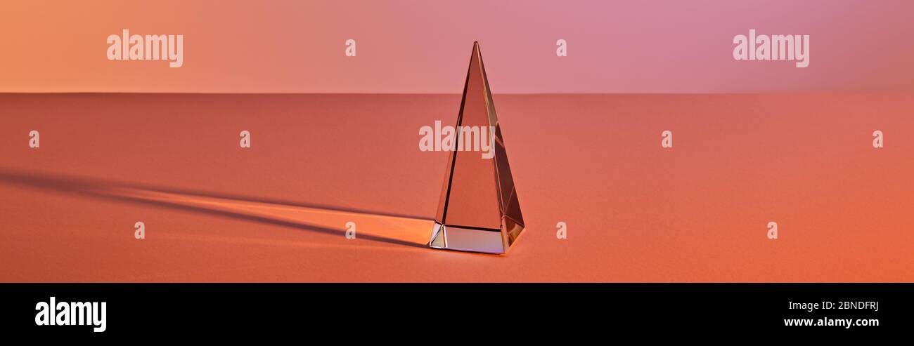 crystal transparent pyramid with light reflection on orange background ...