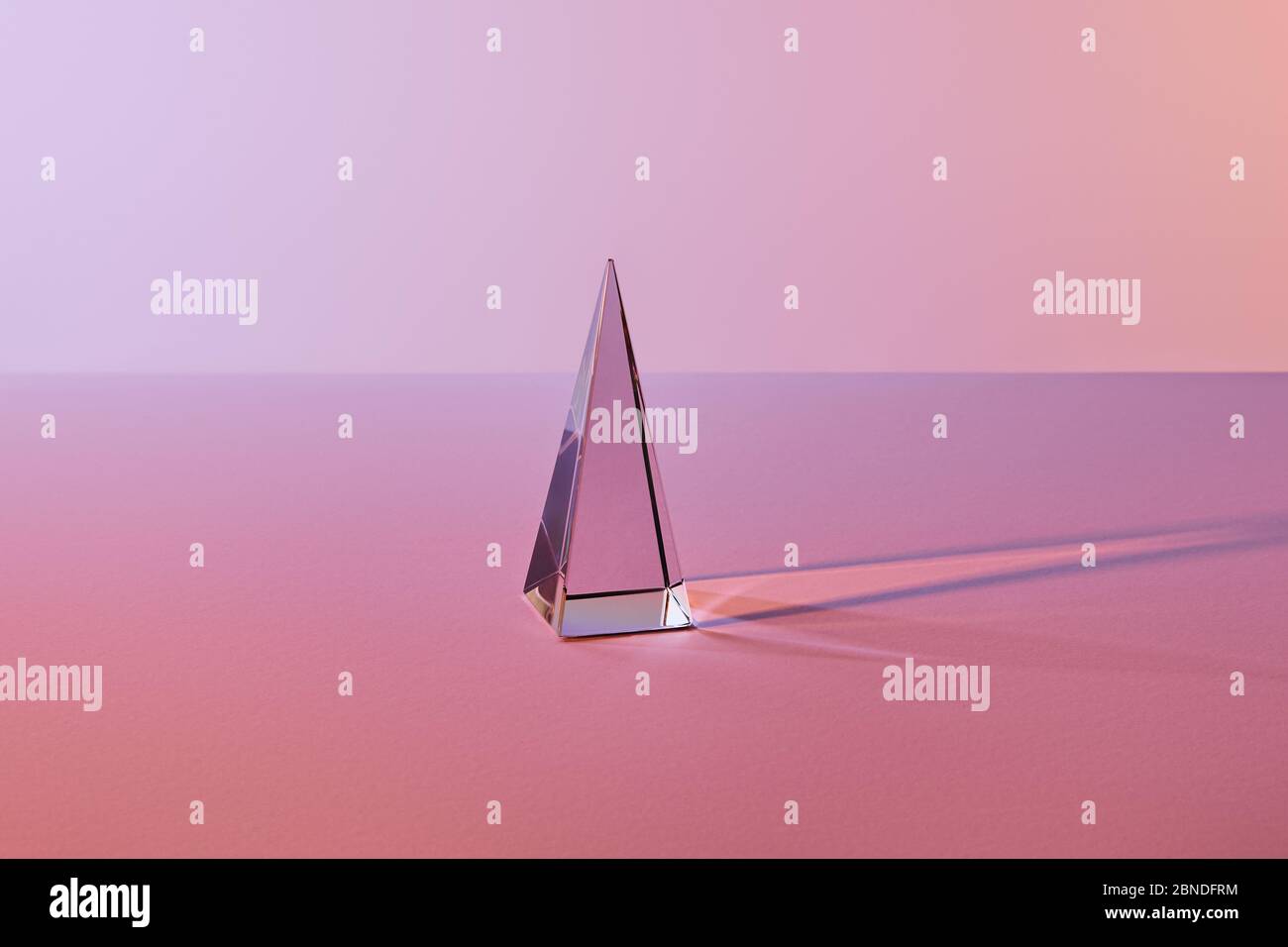 crystal transparent pyramid with light reflection on pink background ...