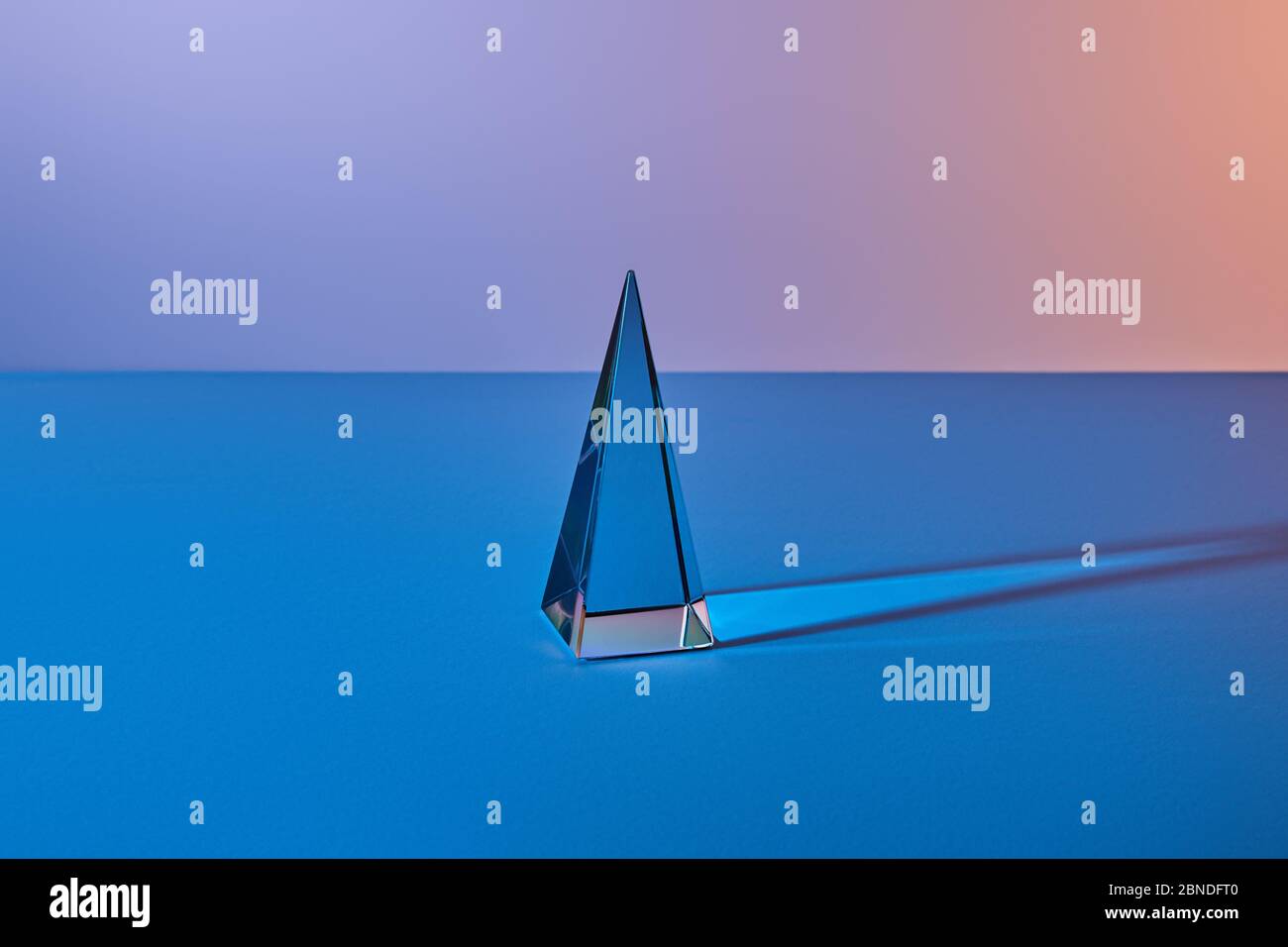 crystal transparent pyramid with light reflection on blue background ...