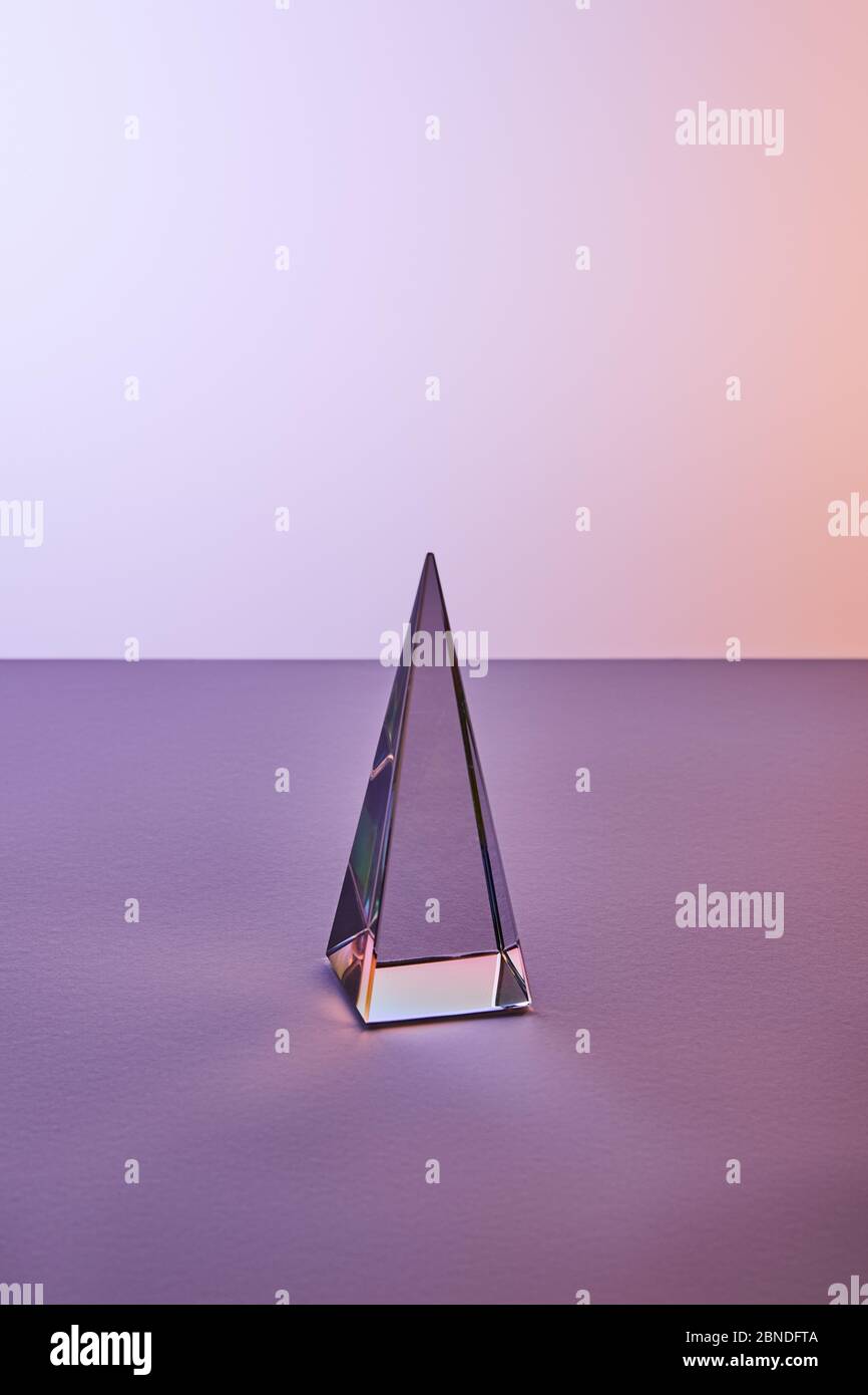 crystal transparent pyramid with light reflection on violet and purple ...
