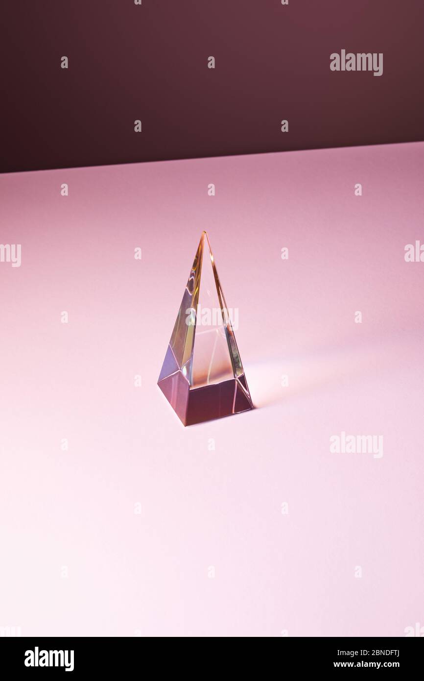 crystal transparent pyramid with light reflection on pink background ...