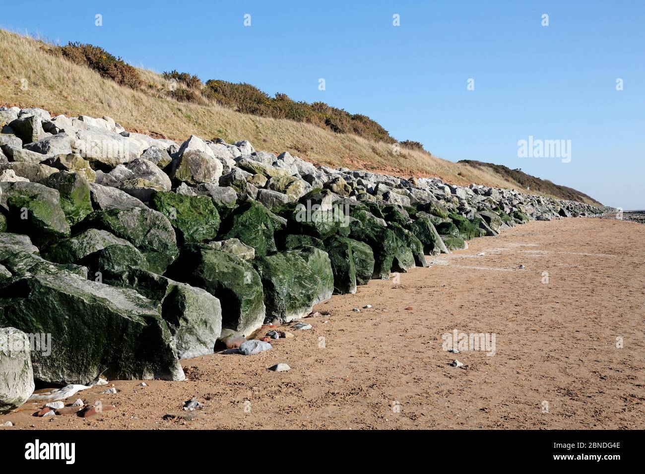 Rocks and boulders placed at bottom of mud and clay cliff to prevent ...