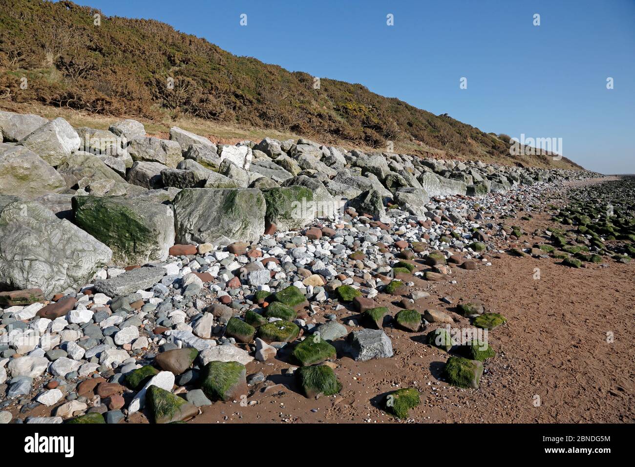 Rocks and boulders placed at bottom of mud and clay cliff to prevent ...