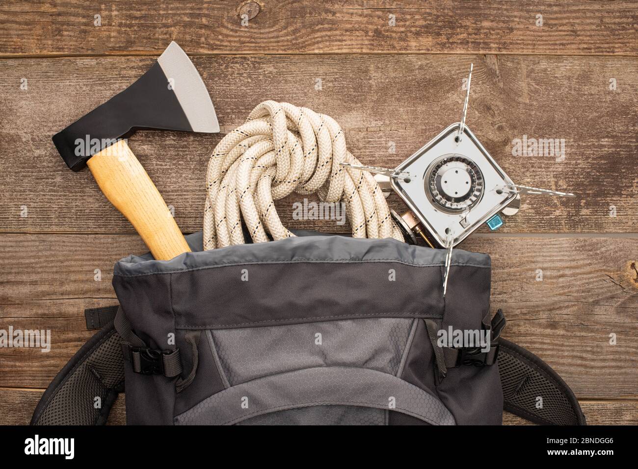 top view of backpack with axe, hiking rope and gas burner on wooden ...