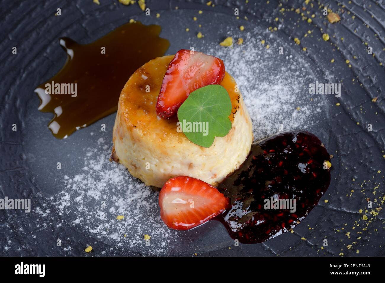 Rice pudding with caramel on top. Strawberries and black plate in a ...