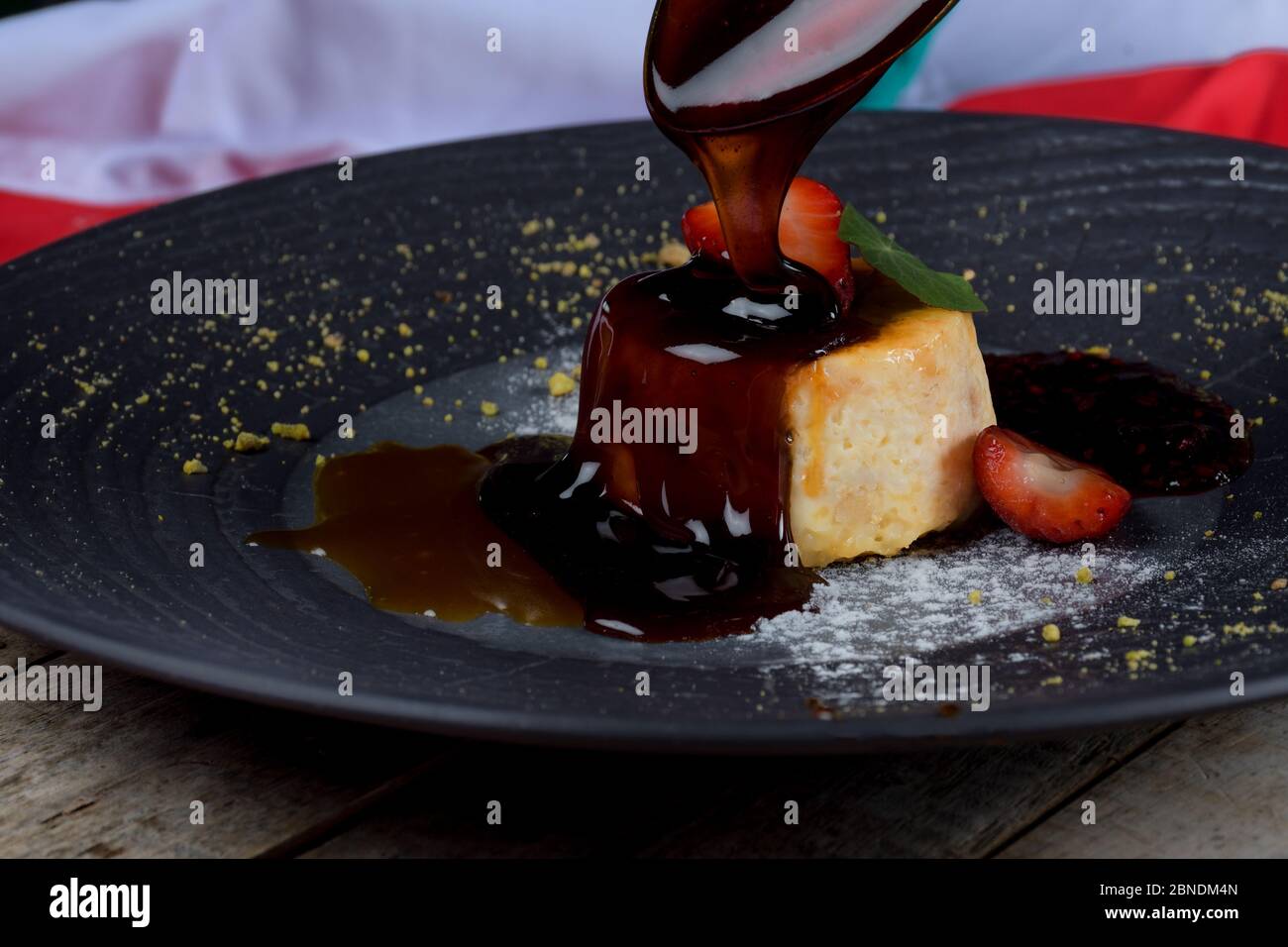 Rice pudding with caramel on top. Strawberries and black plate in a ...