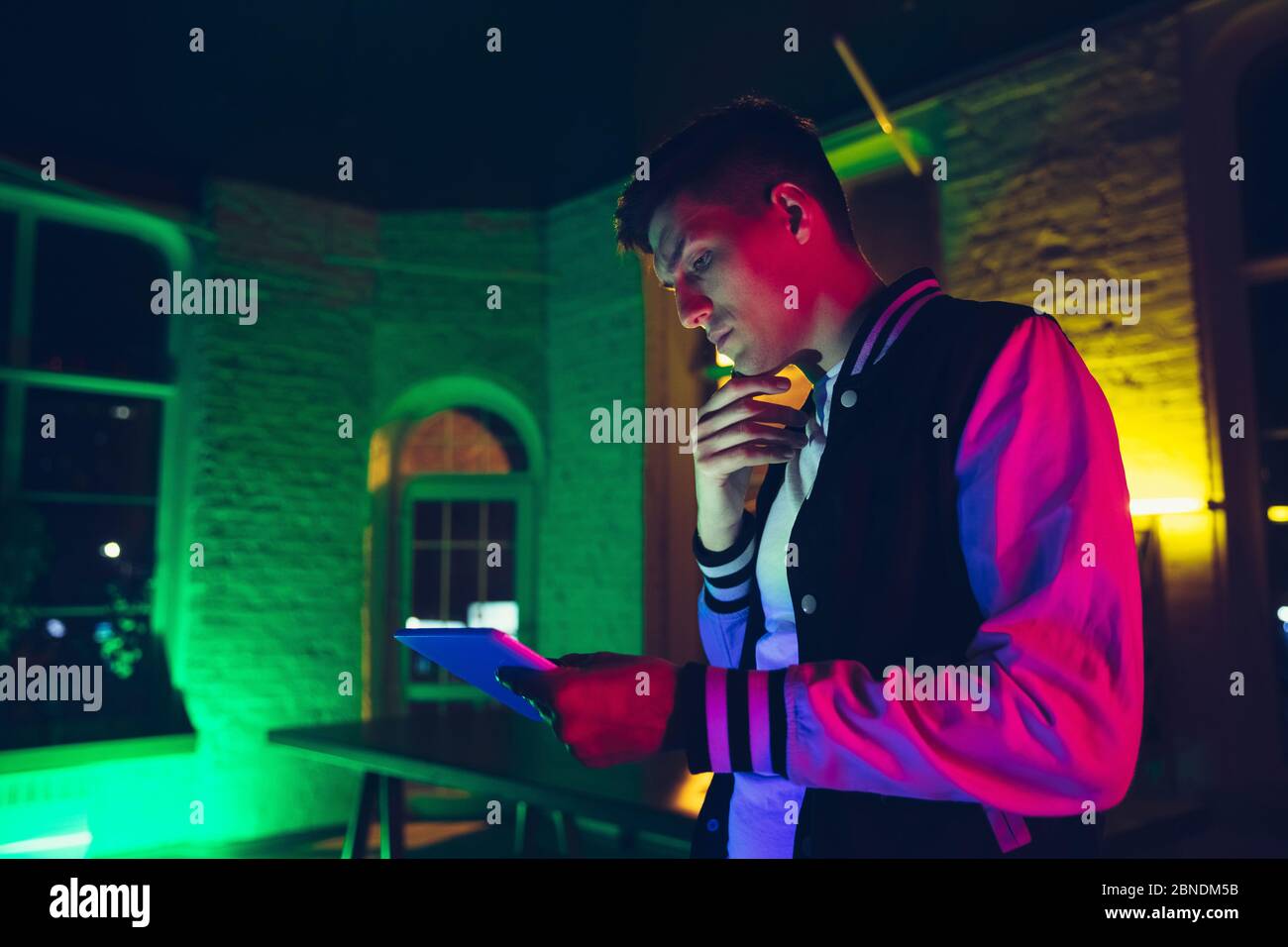 Thinking. Cinematic portrait of stylish man in neon lighted interior ...