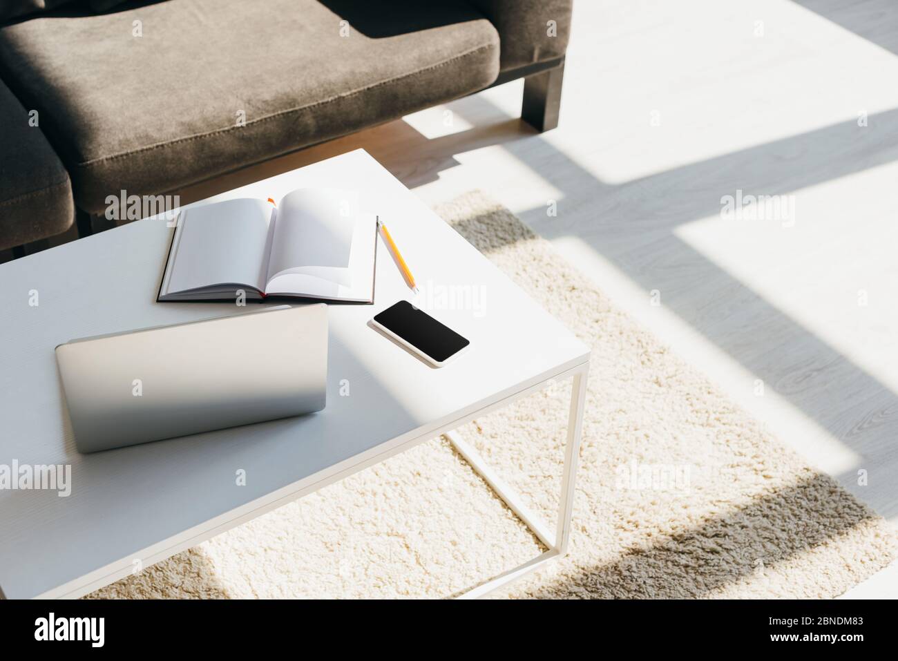 living room with sofa and table with laptop, smartphone, notepad and ...