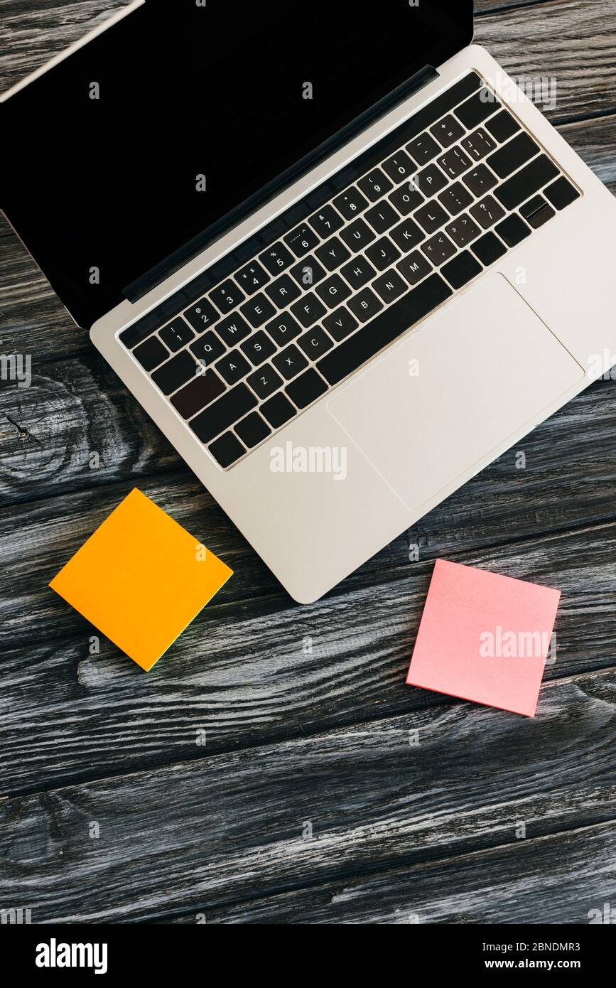 top view of laptop with blank screen and sticky notes on dark wooden ...