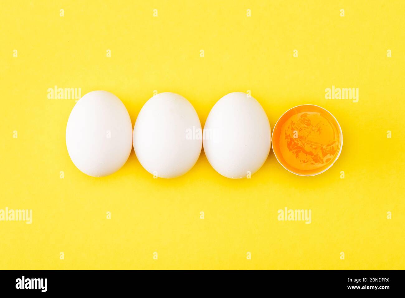 Top view of raw egg half among whole eggs on yellow background Stock ...
