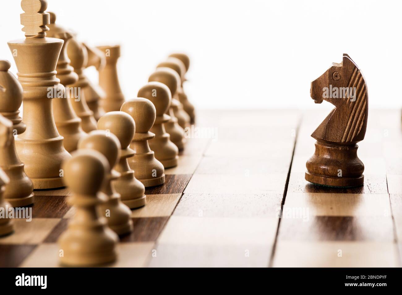Selective focus of brown knight against chess pieces on chessboard ...