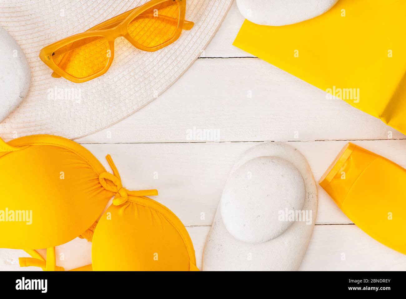 Top view of sun hat, sunscreen with yellow book and sunglasses on white ...