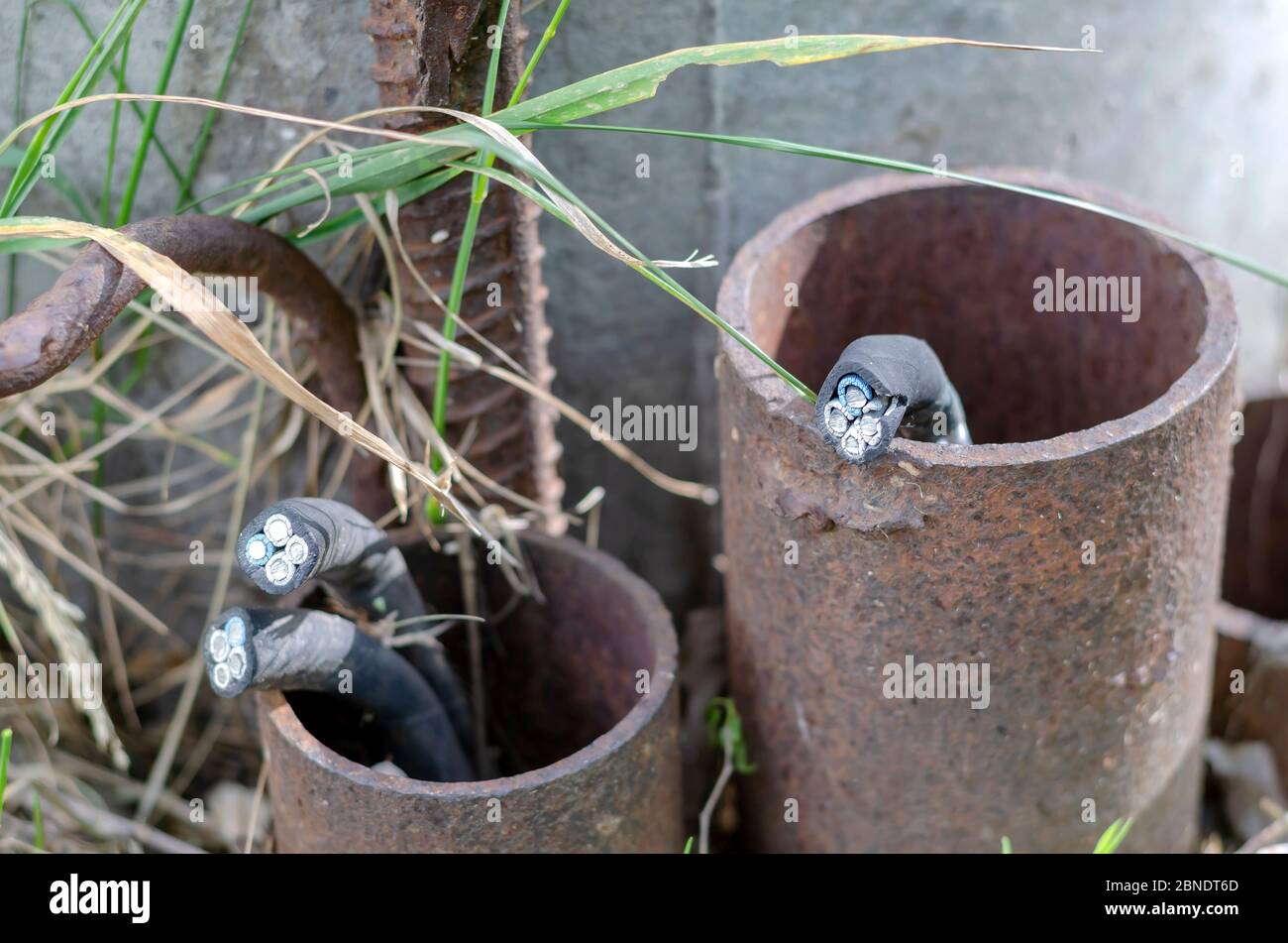 Severed underground electric power cable. Metal pipes stick out of the ...