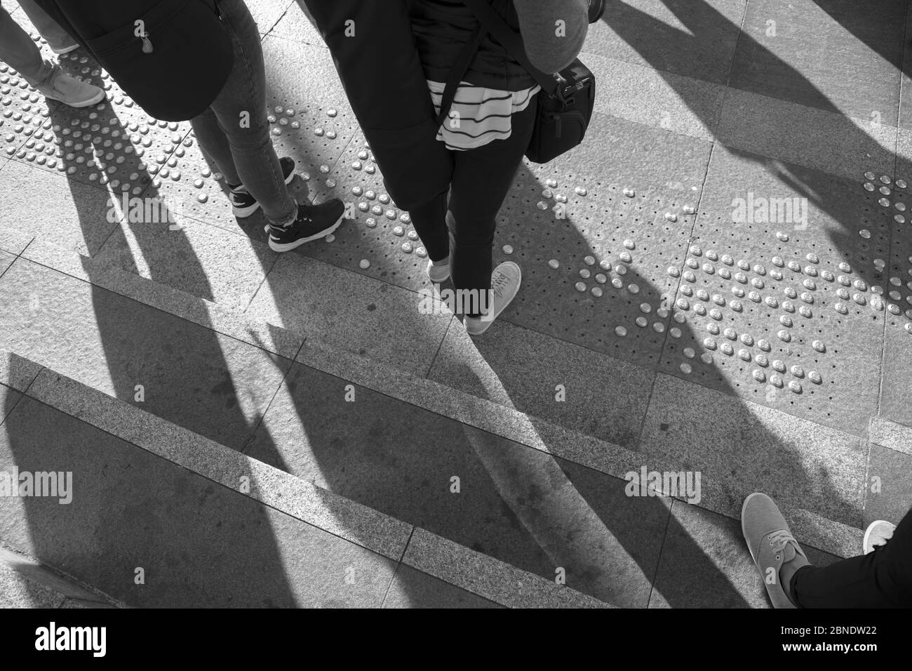 High angle greyscale of the feet of people standing on the ground under ...