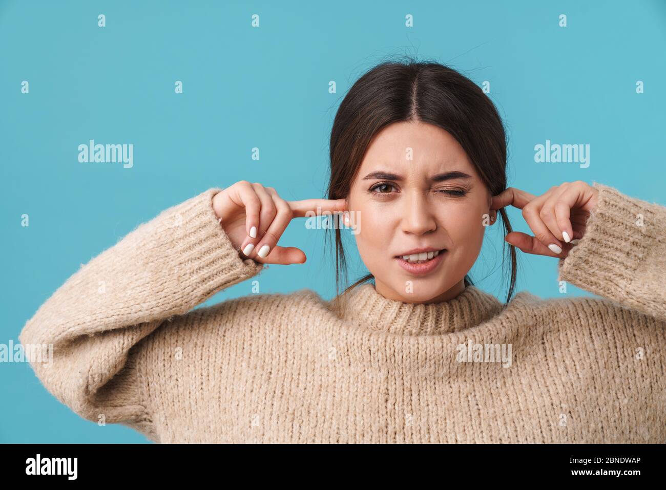 Image of nice young woman winking and plugging her ears isolated over ...