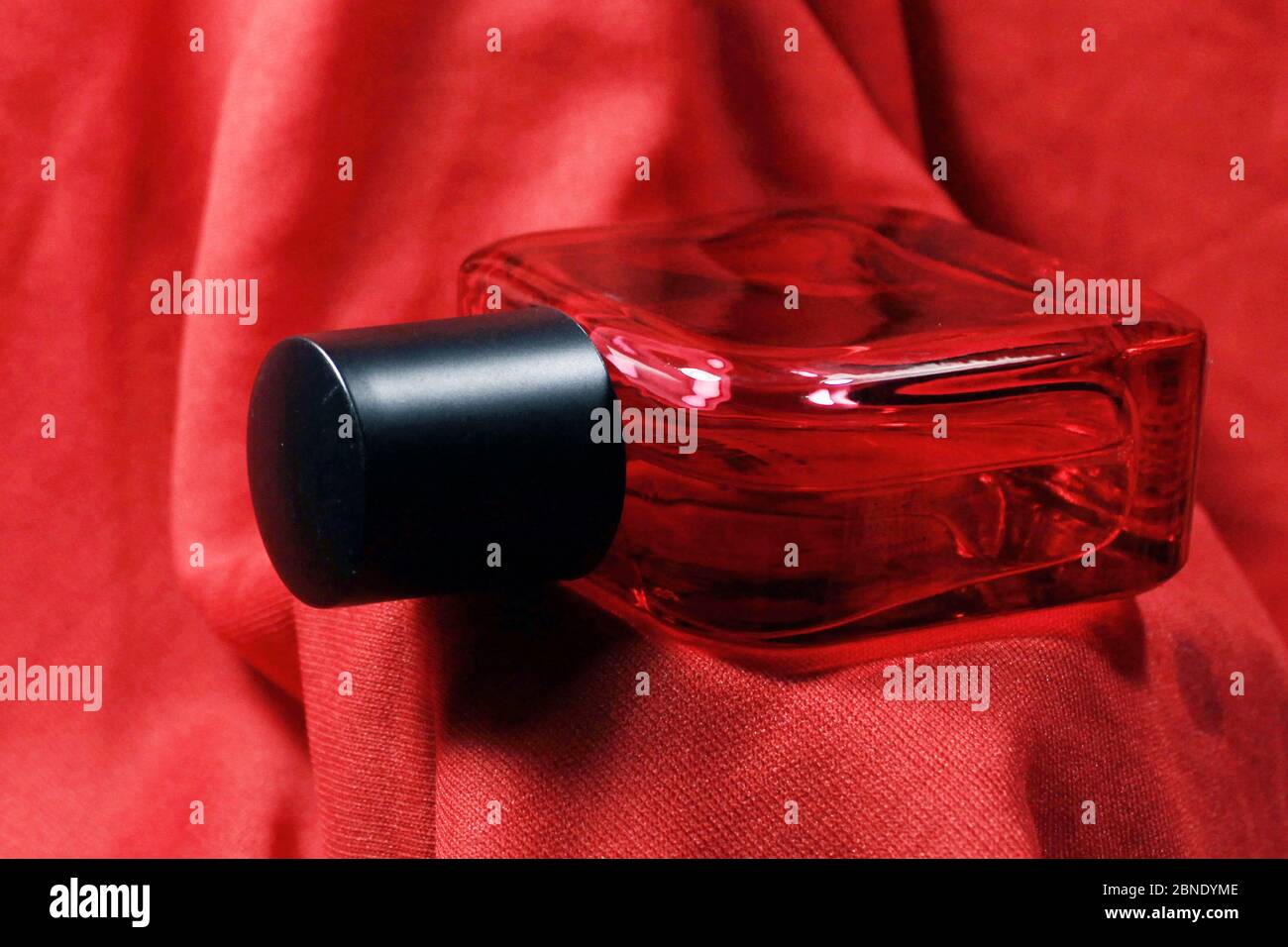 Red color men perfume bottle isolated on red silk background. Red ...