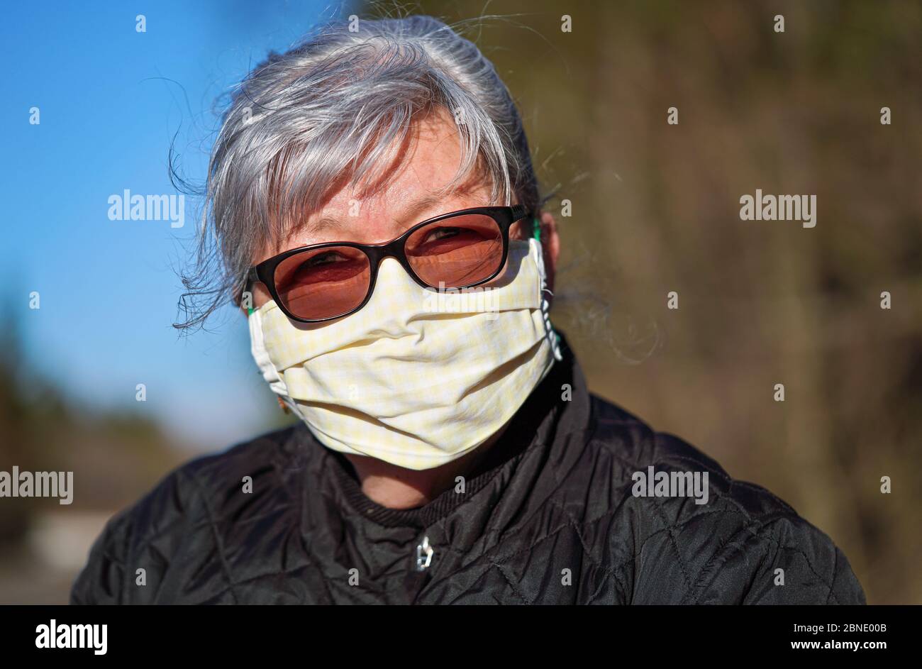 Elderly senior woman with gray hair wearing home made cloth face mouth ...