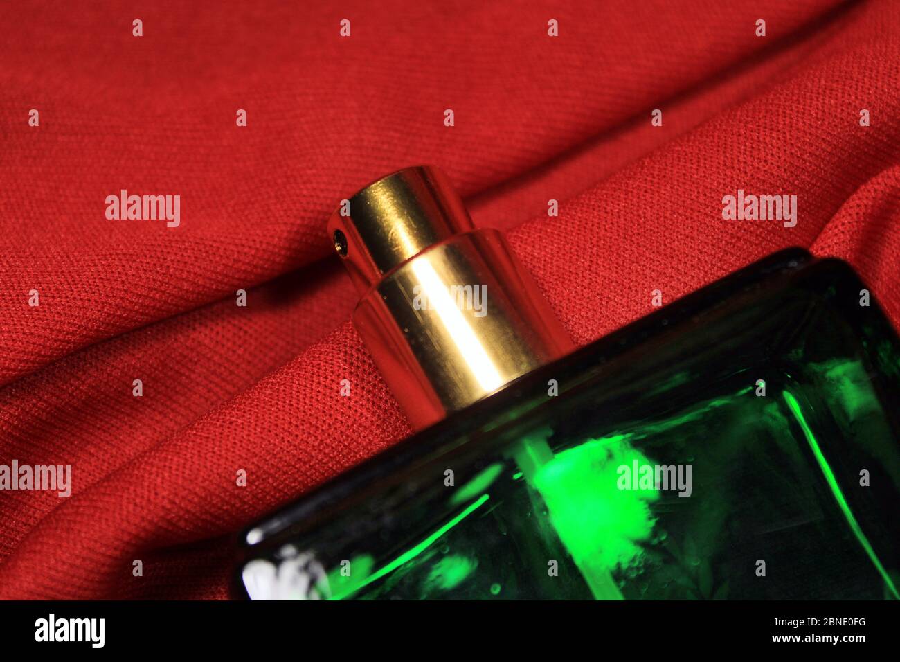 Green color perfume bottle with female accessories isolated on red ...