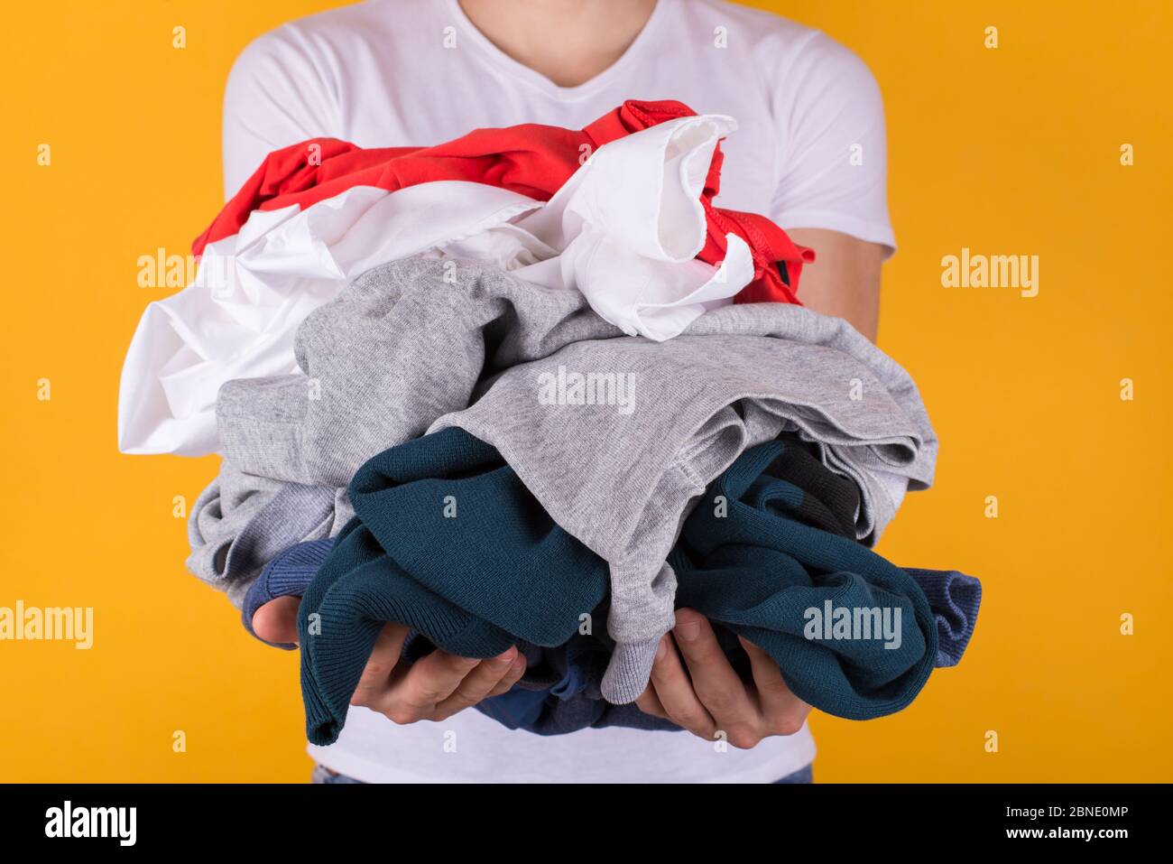 Laundry concept. Cropped front view photo of man holding lots of ...