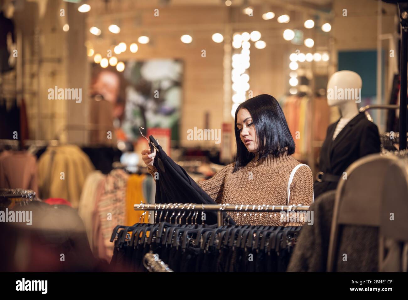 A stylish woman checking out new collection in a clothing store Stock ...