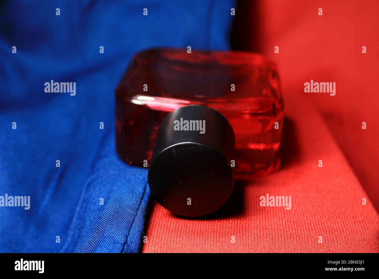 Red color men perfume bottle isolated on blue and red background with ...