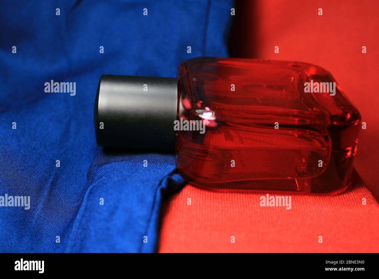 Red color men perfume bottle isolated on blue and red background with ...