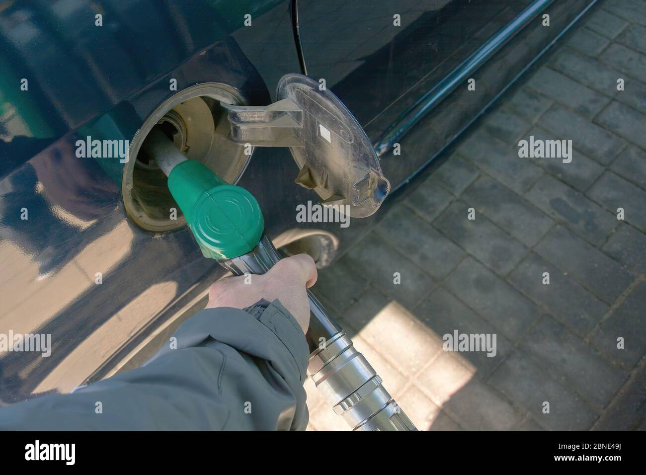 A man's hand holds a green refueling gun. Filling gun inserted into the ...