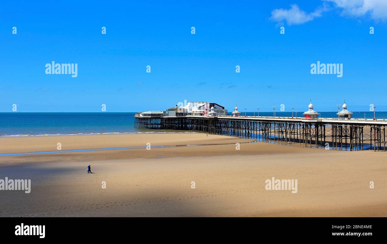 Couple walking along an empty Blackpool beach in the direction of North ...