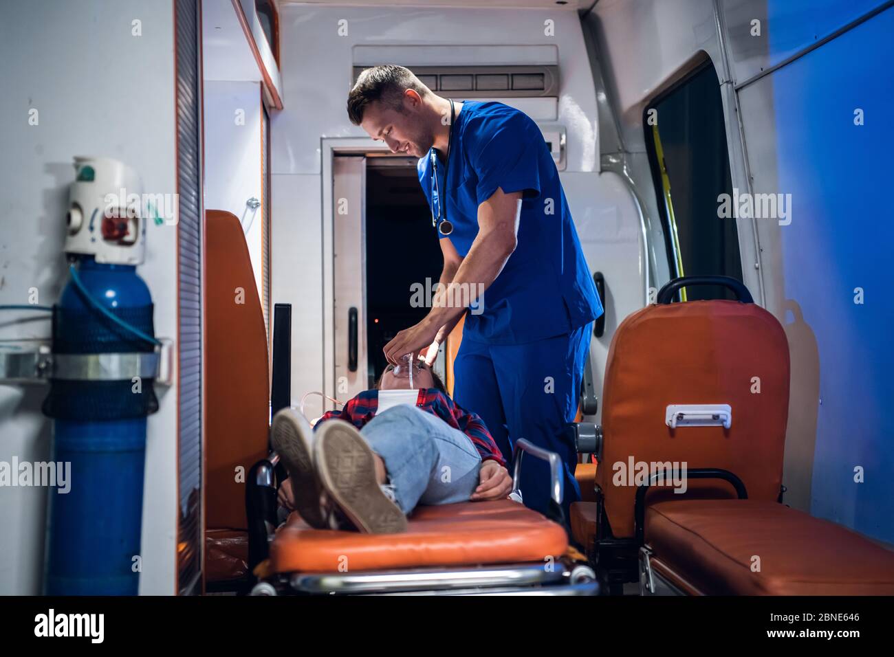 Young paramedic giving an oxygen mask to his female patient in an ...