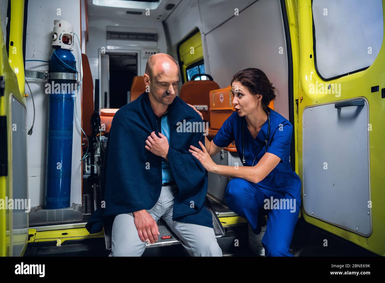 Female paramedic talking to an injured man trying to comfort him, the ...
