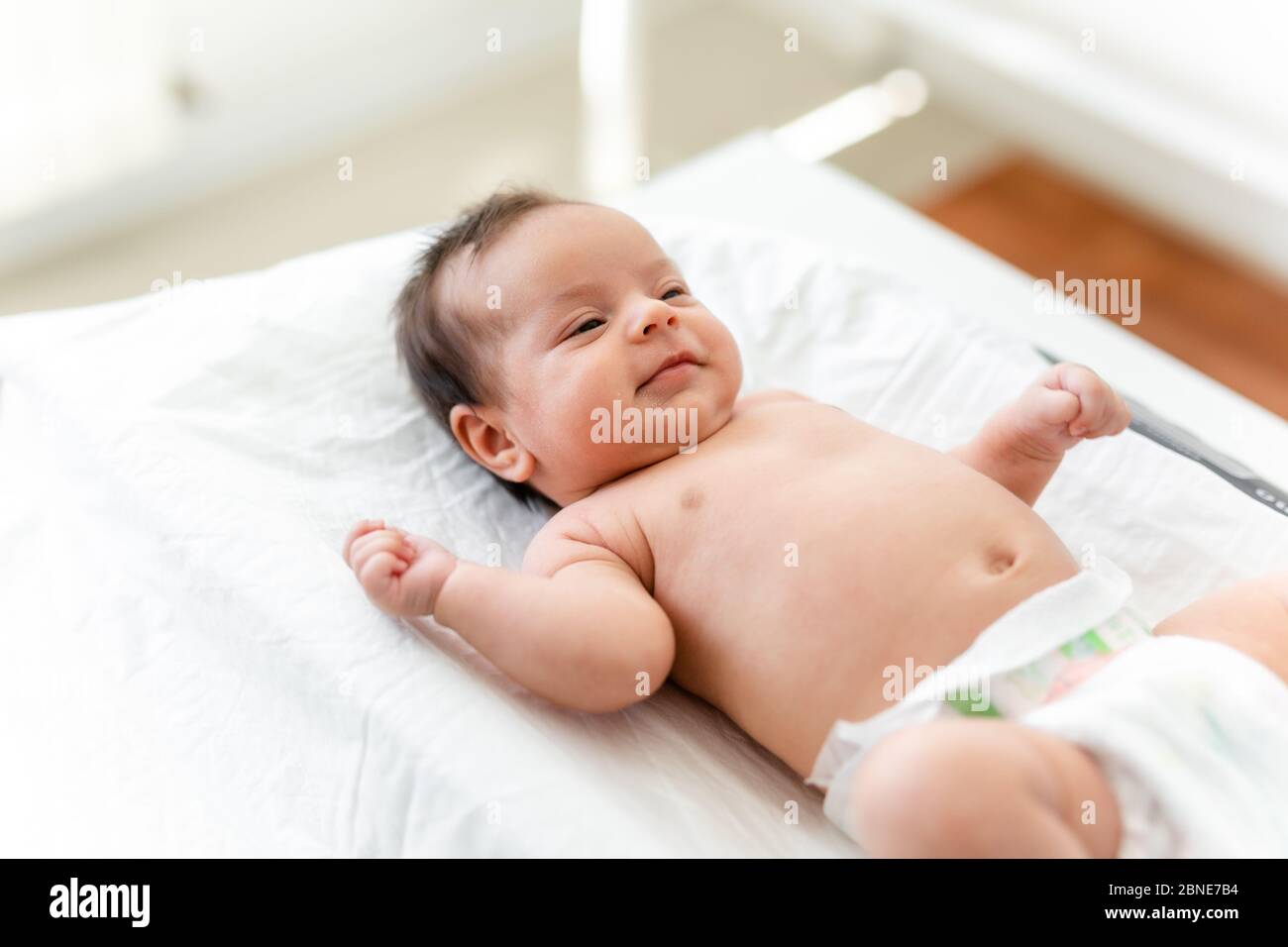 Adorable beautiful newborn baby cradled in its mothers hands looking up ...