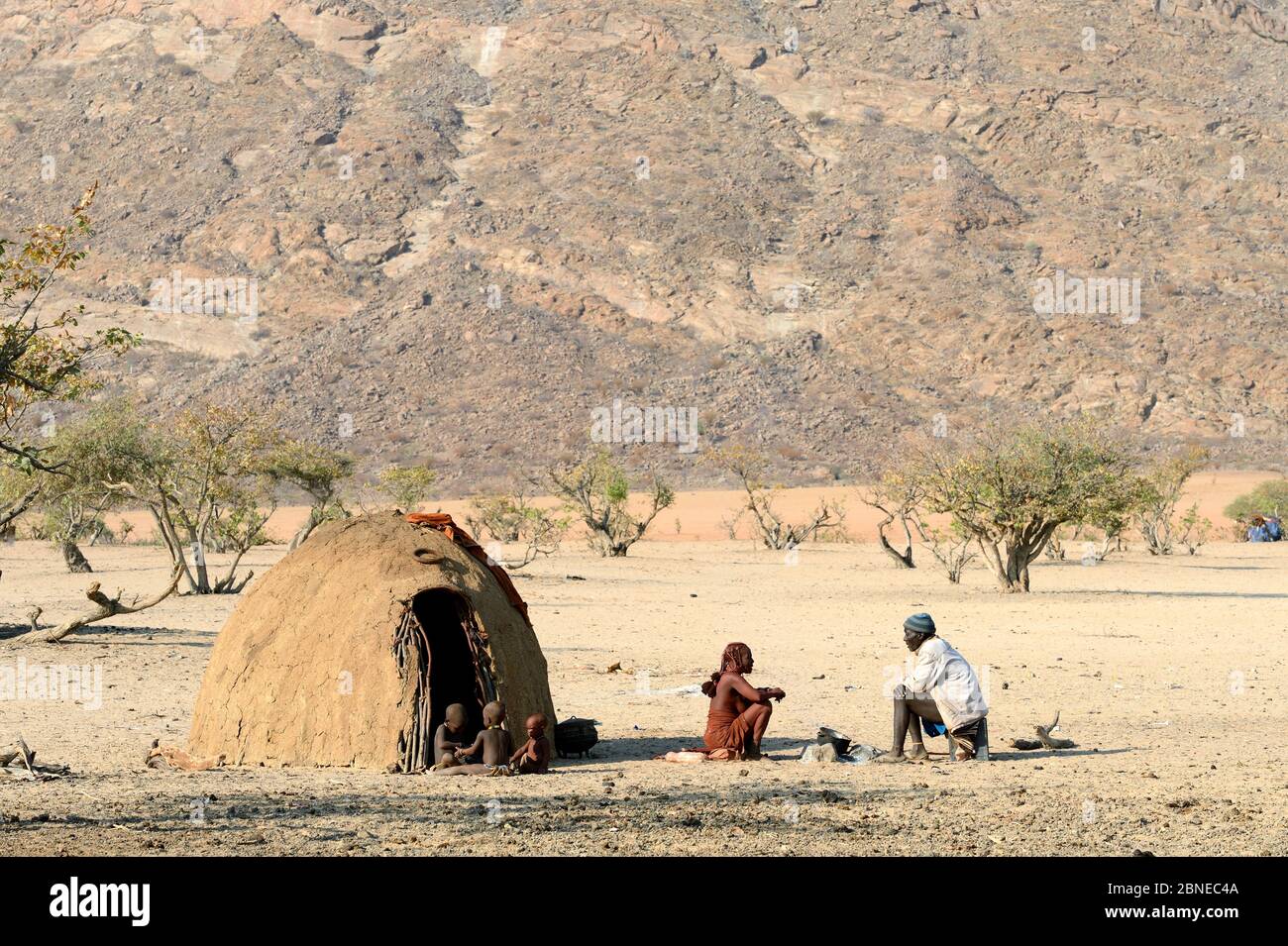 Himba family beside traditional mud hut, Marienfluss Valley during the ...