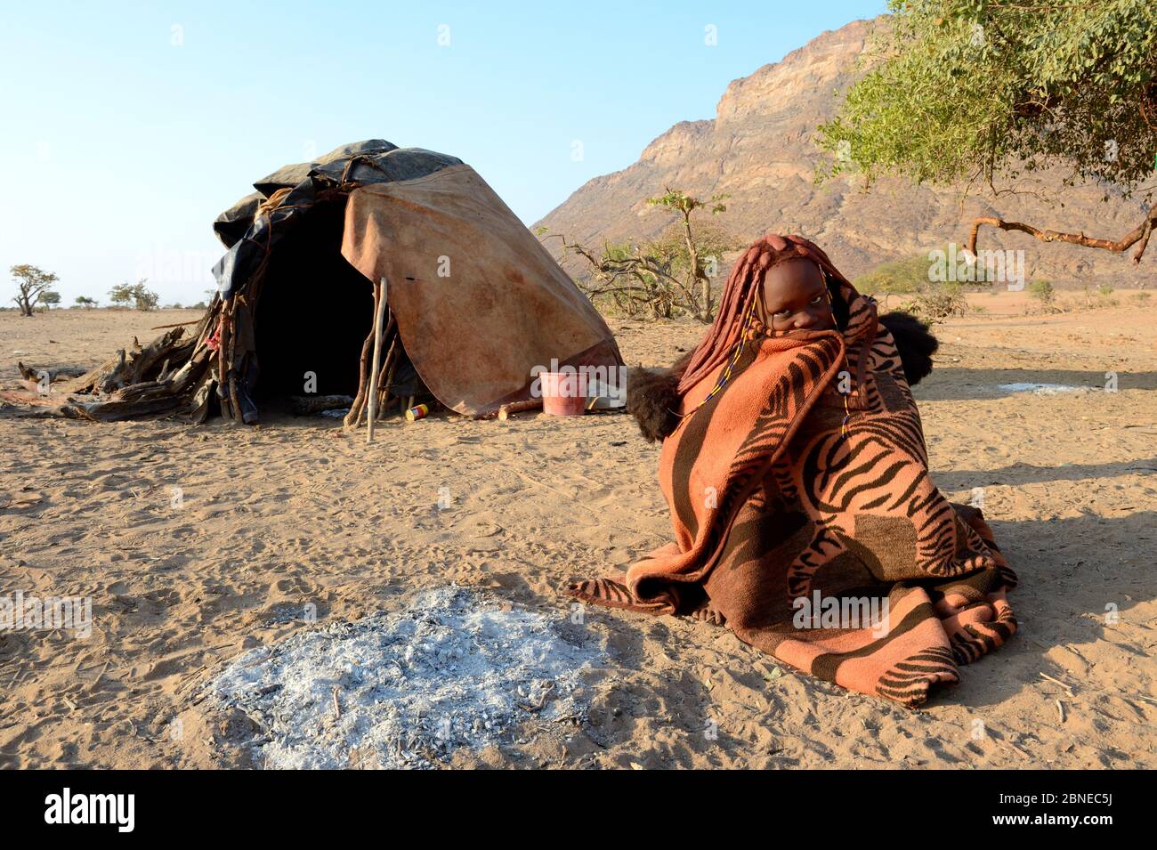 Himba Woman Wrapped Up In A Blanket Next To Her Open Fire With Her Mud