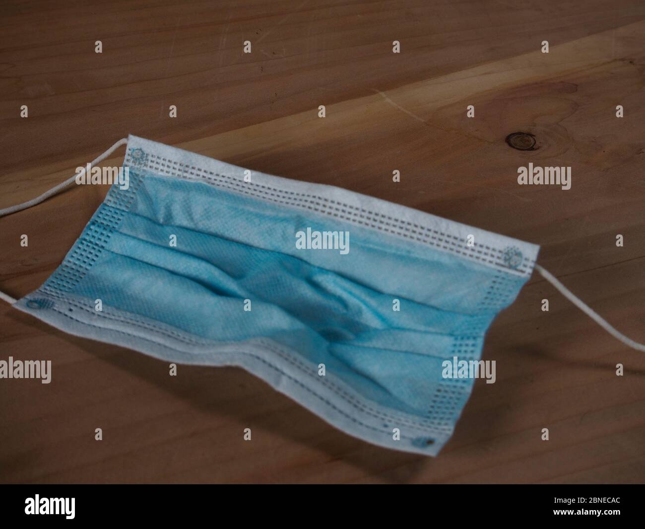 used and broken 3-ply blue surgical mask to cover the mouth and nose ...