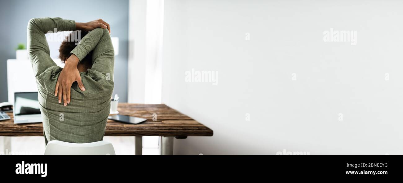 Stretching Arms In Office At Desk Rear View Stock Photo - Alamy