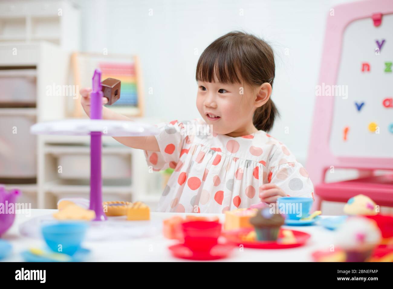 toddler girl prerend play preparing tea party at home Stock Photo - Alamy
