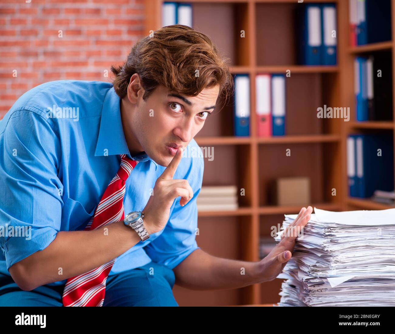 The young employee with excessive work sitting at the office Stock ...