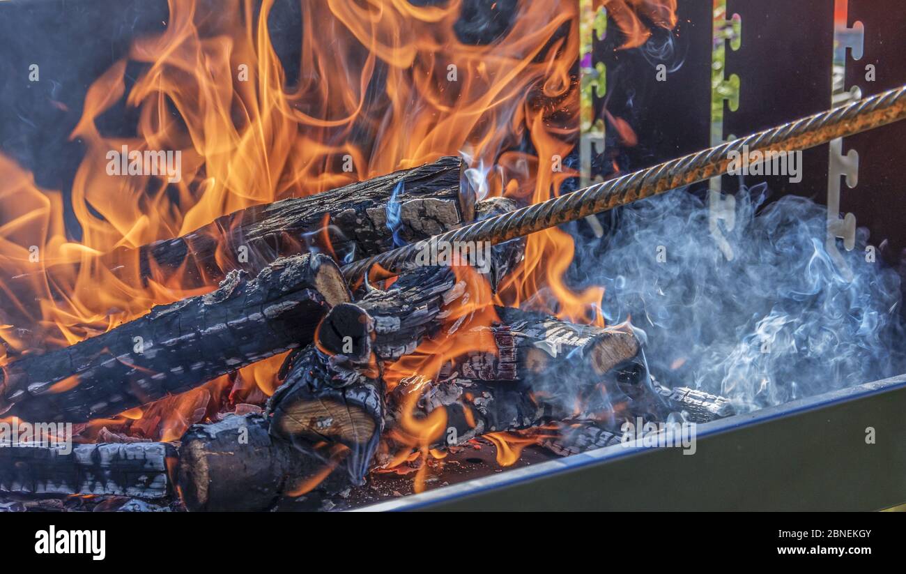 Beautiful closeup of barbecue fire on the grill with flames fire steam ...