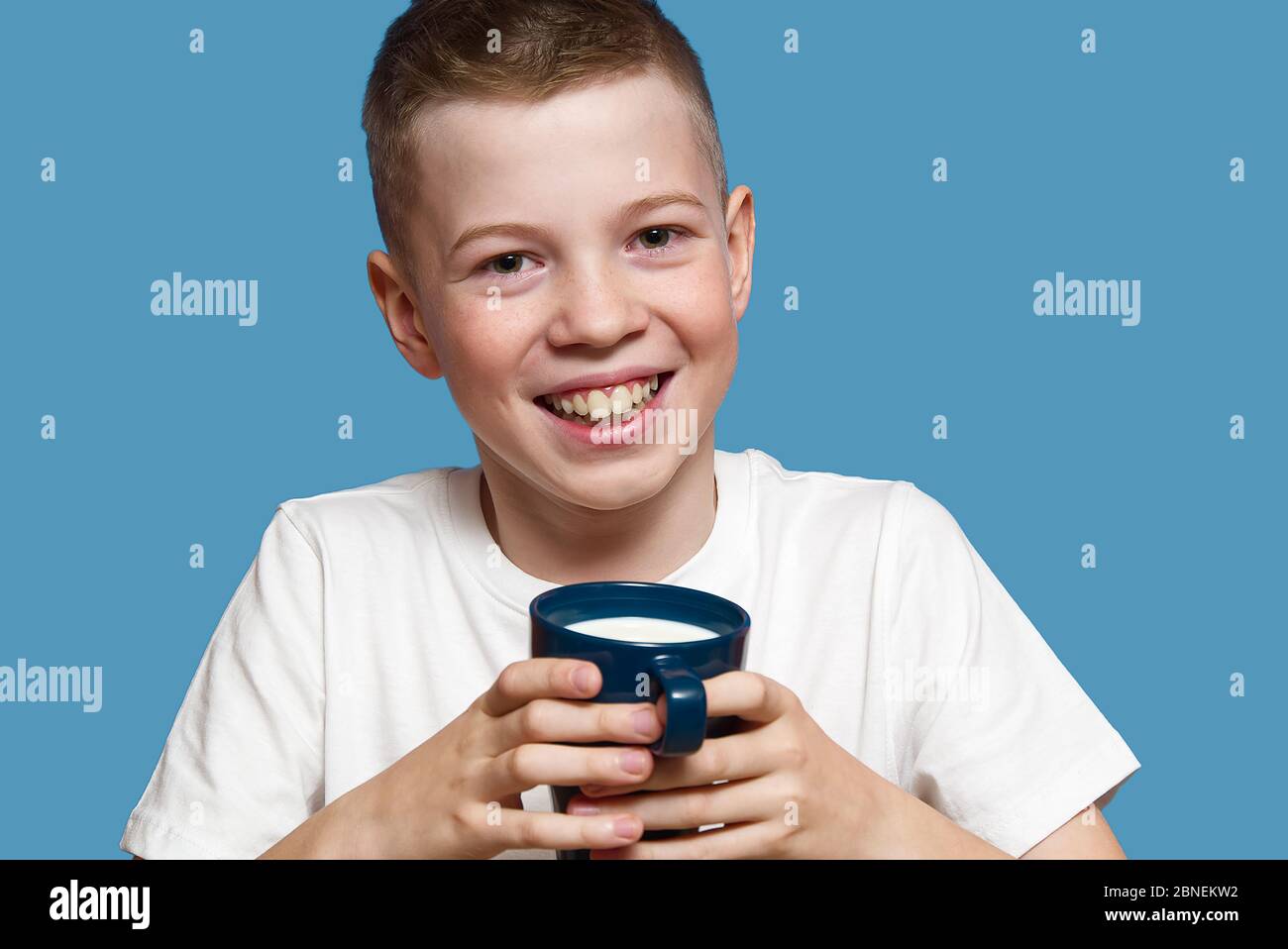 Happy Boy with blue mug of Milk Isolated on blue Background. Smiling ...