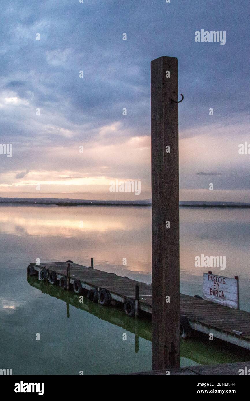Vertical shot of a wooden dock by the sea with the reflection of ...