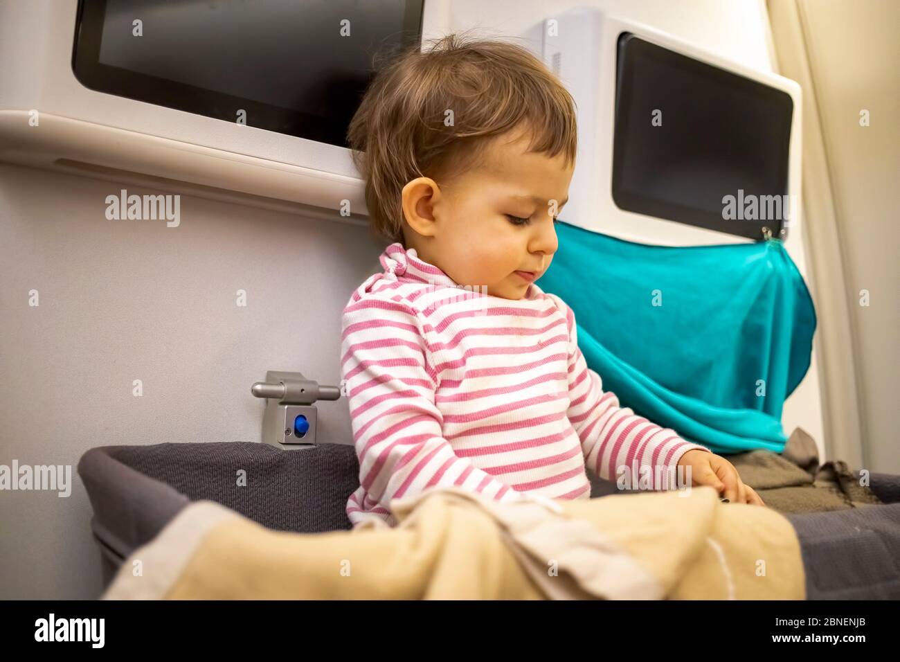 portrait of little cute baby sits in the baby bassinet of the airplane ...