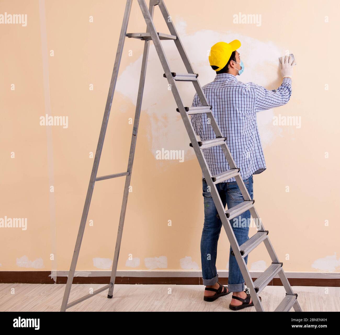 The young contractor sanding wall down with sandpaper Stock Photo - Alamy