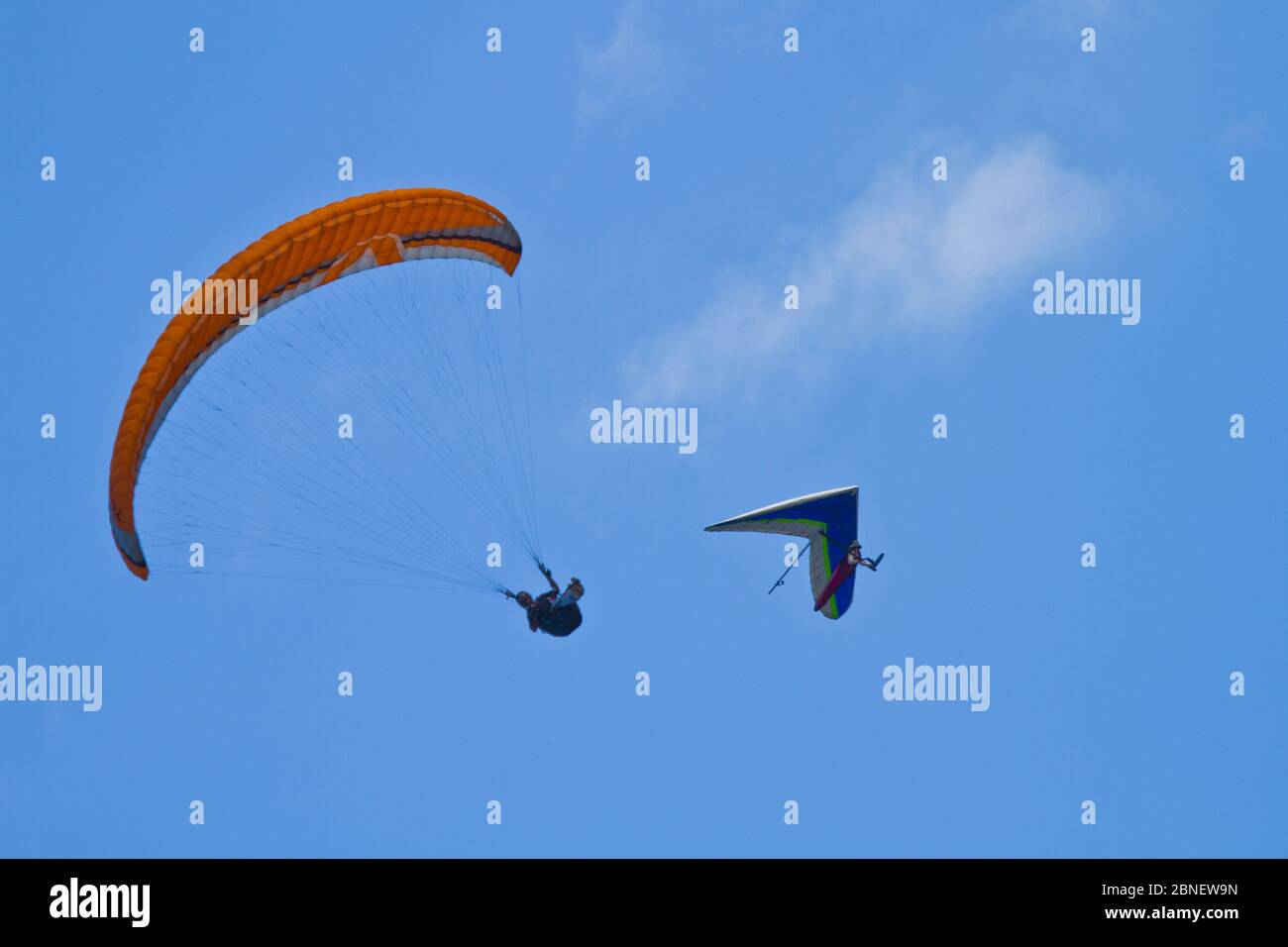 Amazing shot of two humans paragliding and flying on a hang glider ...