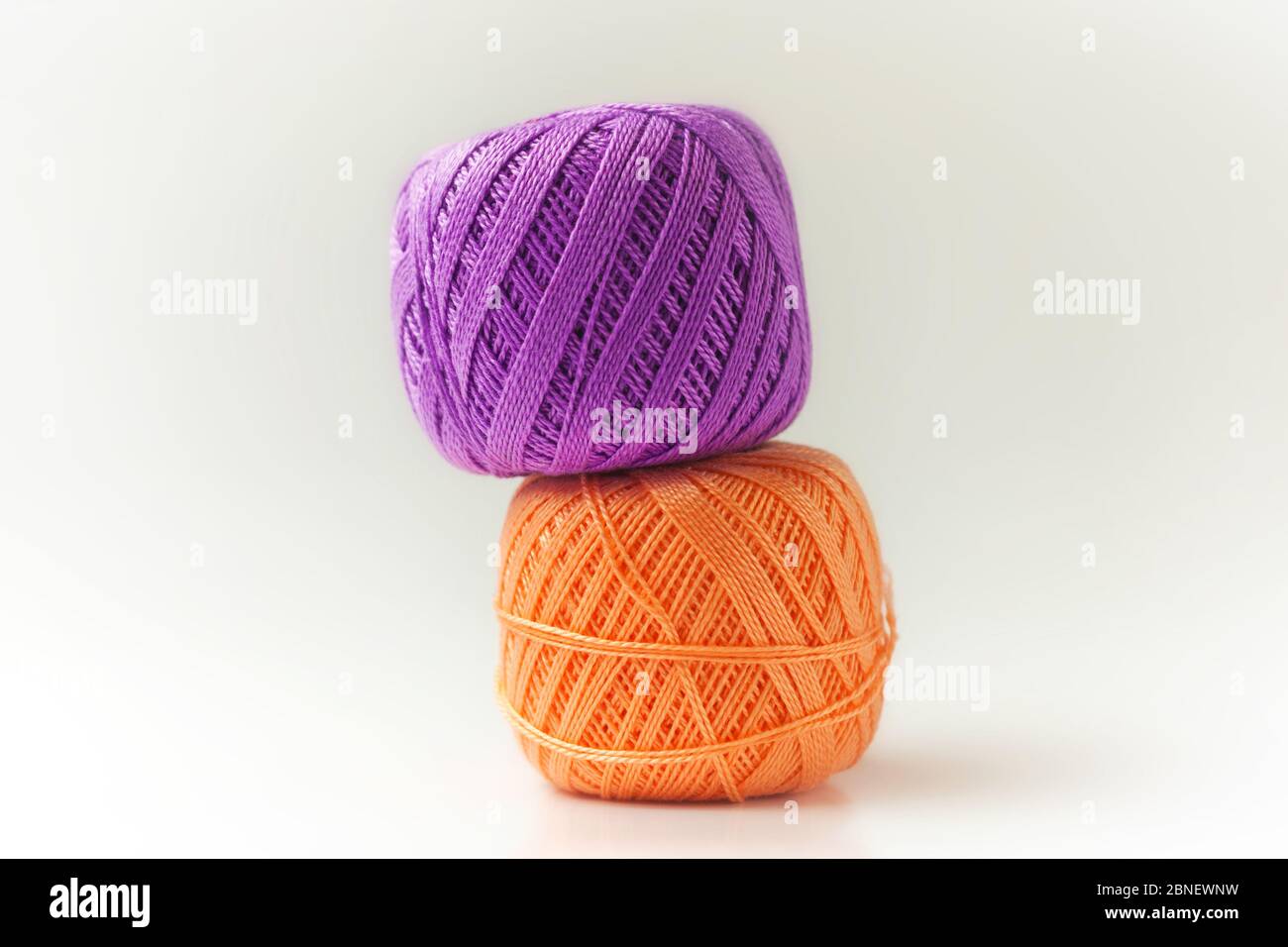 Two skeins of thread in purple and orange. Knitting threads on a white ...
